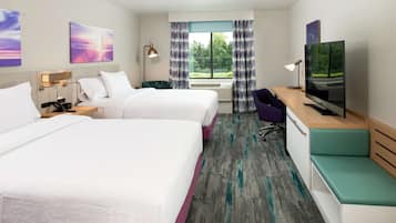 Quarto de hotel com duas camas, televisão, escrivaninha e janela com cortinas.