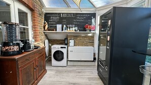 Uma cozinha compacta com máquina de café, máquina de lavar, geladeira e cardápio em lousa.