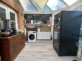 Uma cozinha compacta com máquina de café, máquina de lavar, geladeira e cardápio em lousa.