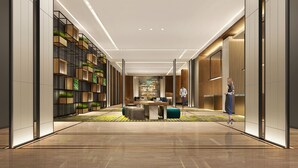 Um interior moderno com um balcão de recepção central, área de estar e uma parede com jardineiras embutidas.