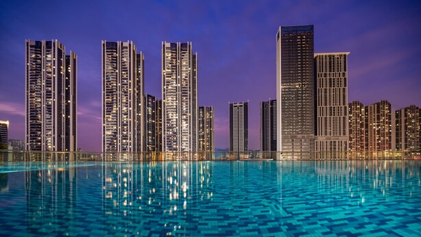 Paisagem urbana noturna com edifícios altos e um espelho d'água refletor.
