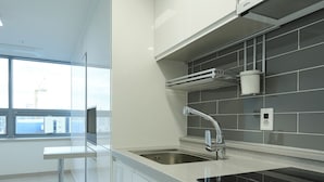 Cozinha moderna com máquina de lavar e secar embutidas, pia de aço inoxidável e janela com vista para a cidade.