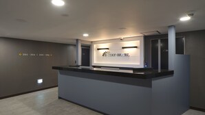 Uma receção de hotel com design moderno, apresentando um ecrã digital e uma placa acima.