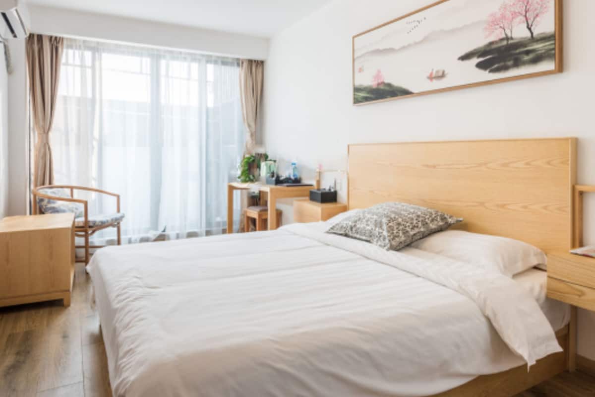 Quarto com uma cama grande, uma escrivaninha, uma cadeira e um quadro na parede.