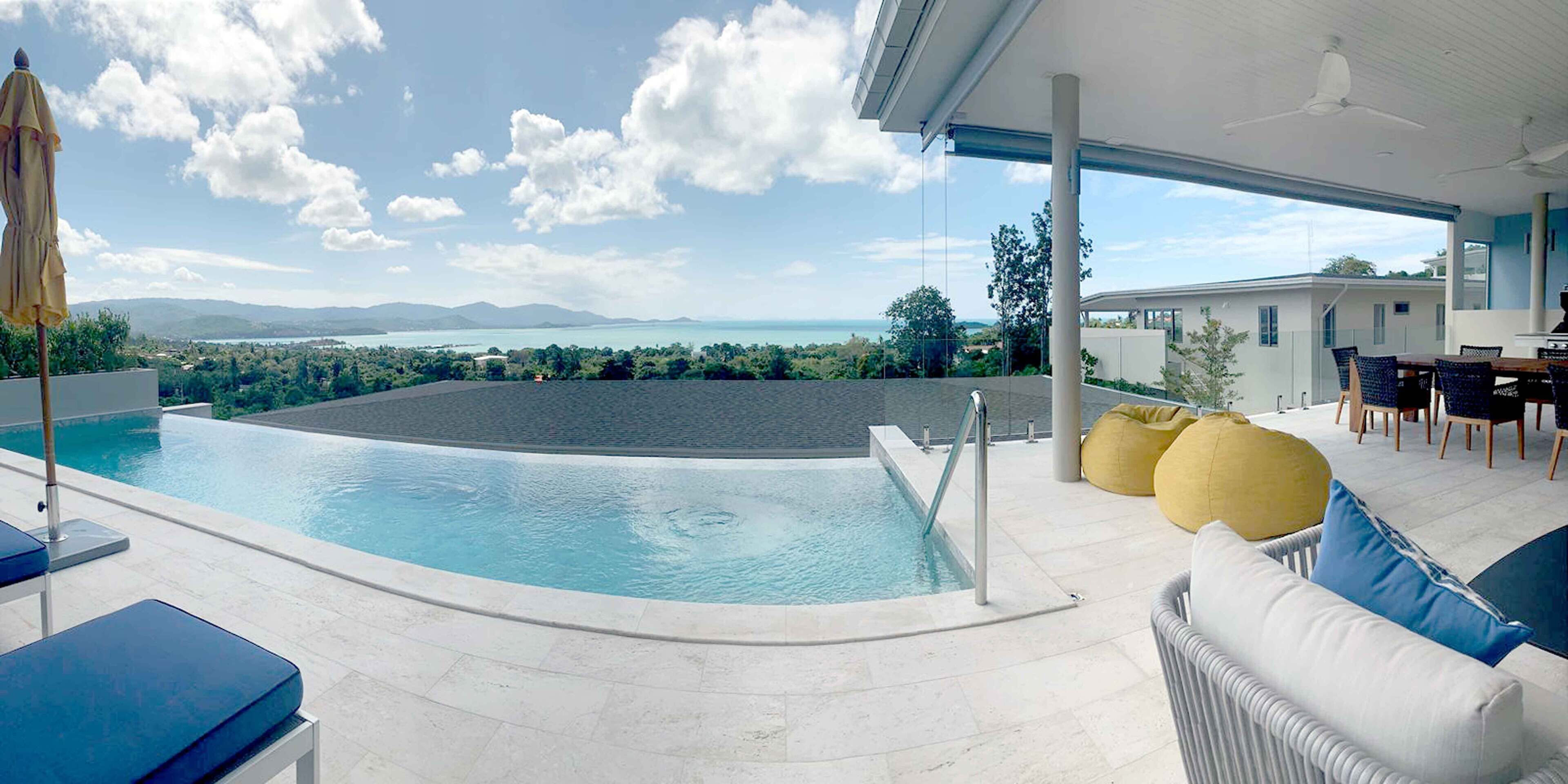 Uma área moderna com piscina ao ar livre, vista para o mar e montanhas, espaço coberto para relaxar e um espaço para refeições.