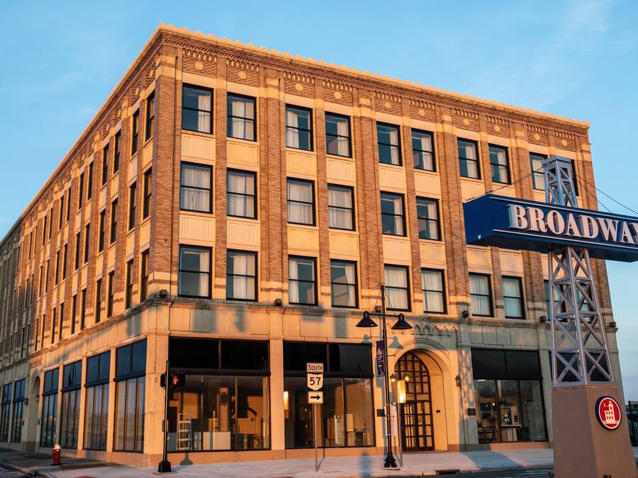 Um edifício histórico com uma placa 'Broadway', grandes janelas e uma entrada imponente.