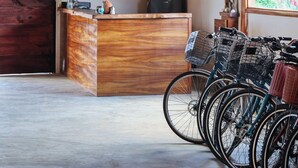 Uma área de recepção com uma mesa de madeira, um computador e um suporte para bicicletas.