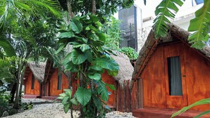 Um resort tropical com cabanas de telhado de palha, rodeado por vegetação exuberante e um caminho de cascalho.