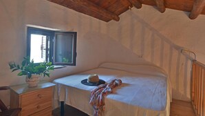 Quarto com cama, janela, cômoda e planta em vaso.