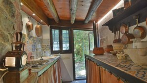Uma cozinha rústica com vigas de madeira, parede de pedra e painel de azulejos.
