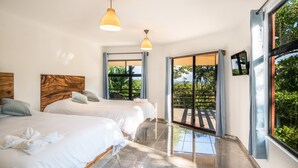 Quarto de hotel moderno com duas camas, janelas amplas e uma varanda.