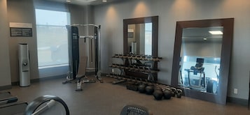 Centro de fitness com barra de exercícios, banco de peso, halteres e pesos russos.