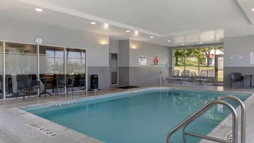 Piscina interior com marcações claras, um relógio e um aviso sobre não engolir água.