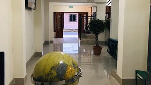 Um corredor com um globo, uma planta em vaso e uma escada ao fundo.