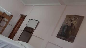 Quarto com cama, espelho e pintura na parede.