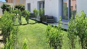 Uma casa moderna com um gramado bem cuidado e uma área de varanda com móveis de exterior.