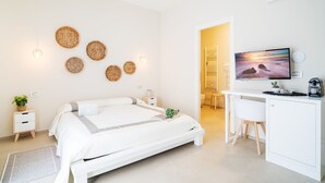 Um quarto moderno com cama, mesas de cabeceira, escrivaninha e televisão.