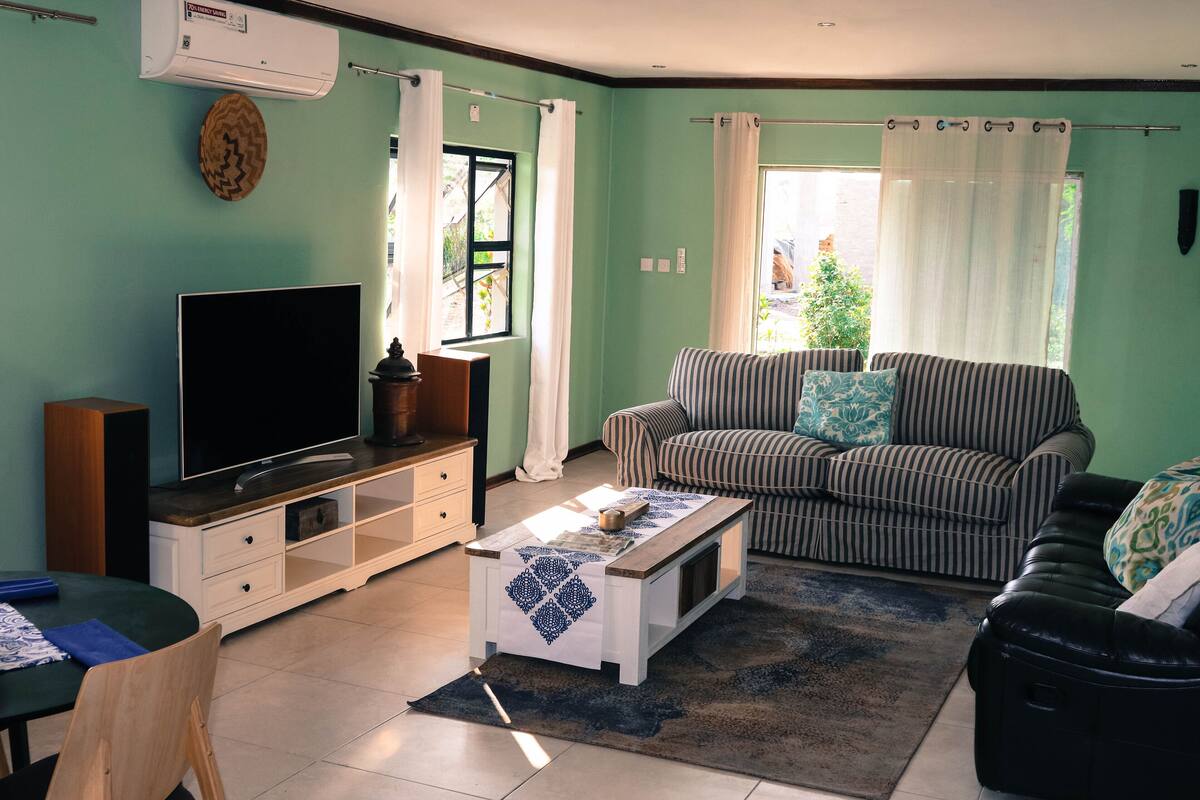 Uma sala de estar com televisão de tela plana, um sofá, uma mesa de centro e um móvel para TV.