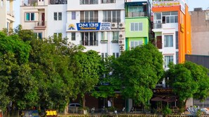 Um edifício de vários andares com uma placa visível para 'DM 135 Homestay', indicando um hotel ou estabelecimento de hospedagem.