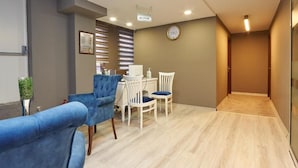 Uma área de recepção moderna, com balcão de atendimento, relógio na parede e um espaço de estar com cadeiras e um sofá.