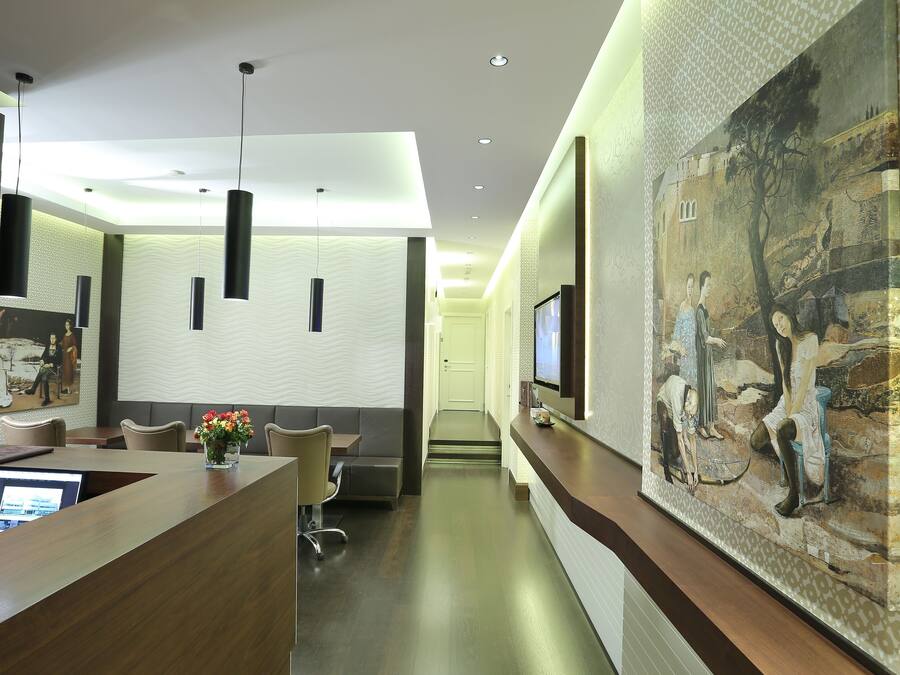 Uma área de recepção de hotel moderna, com um balcão de atendimento espaçoso, zona de estar e um quadro grande na parede.