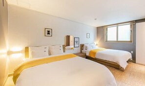 Quarto de hotel com duas camas, uma janela grande e um espelho.