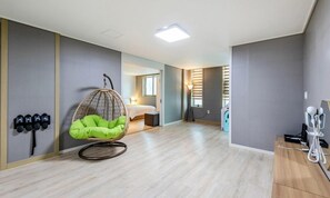 Quarto de hotel moderno com uma cadeira suspensa, uma cama, uma escrivaninha e uma máquina de lavar roupa.