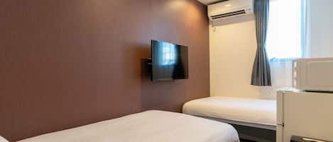 Quarto de hotel com duas camas, televisão de tela plana na parede, ar condicionado, micro-ondas e janela com cortinas.