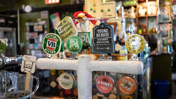 Um bar com diversas torneiras de cerveja, incluindo marcas como Victoria Bitter, Goose IPA e Young Henry's Newtowner.
