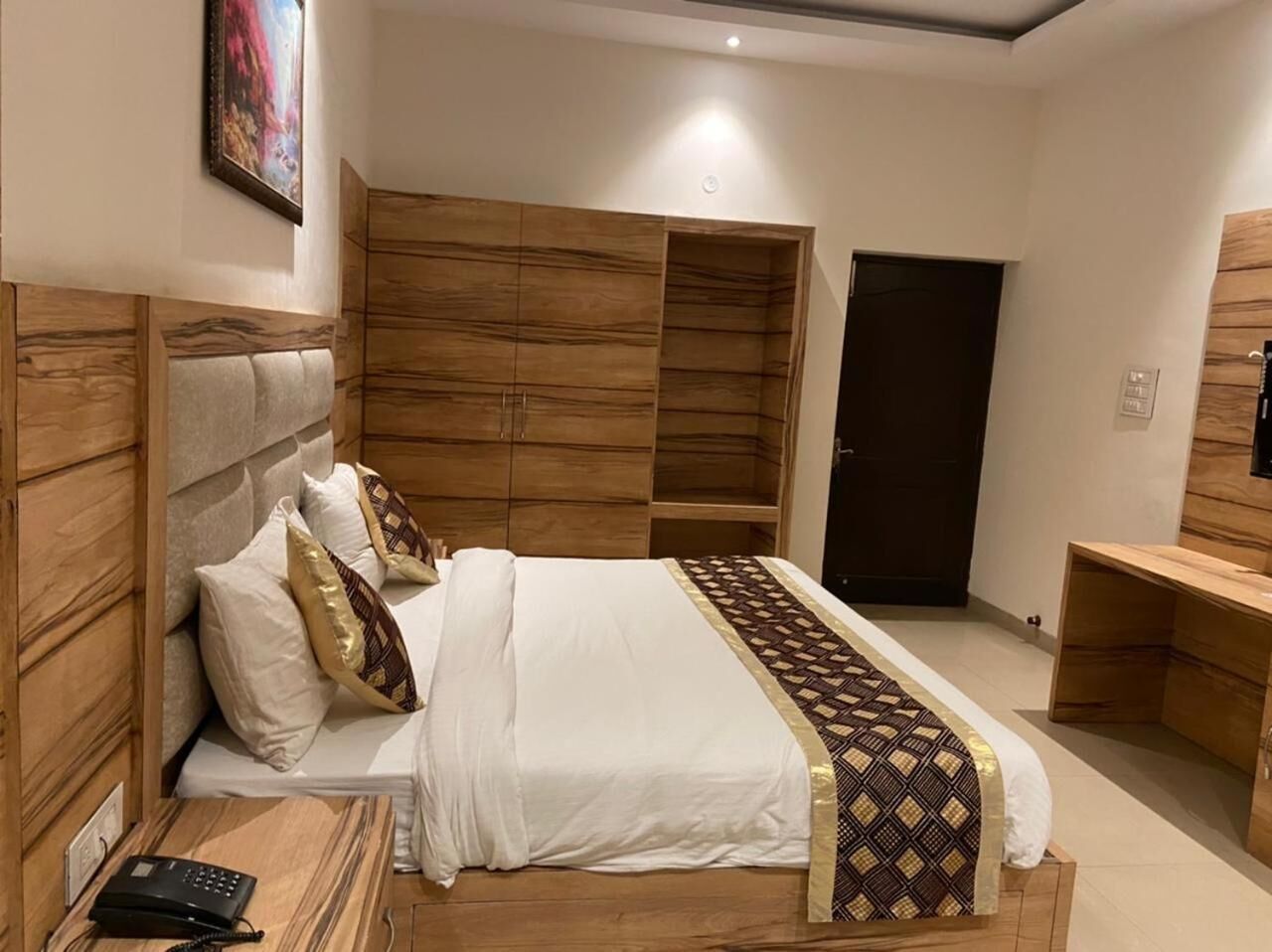 Quarto com cama, cabeceira de madeira, mesa de cabeceira e guarda-roupa.