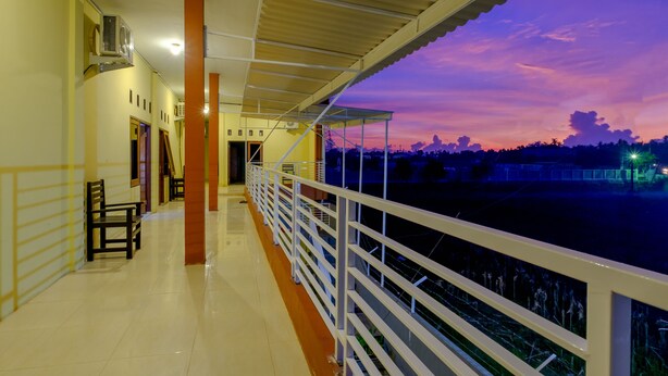 Uma varanda com guarda-corpo, um banco e vista para o céu ao entardecer.