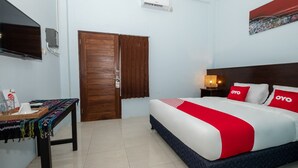 Quarto de hotel com cama, televisão, escrivaninha e porta.