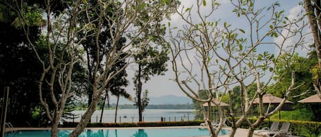 Piscina com vista para um lago e montanhas ao longe.
