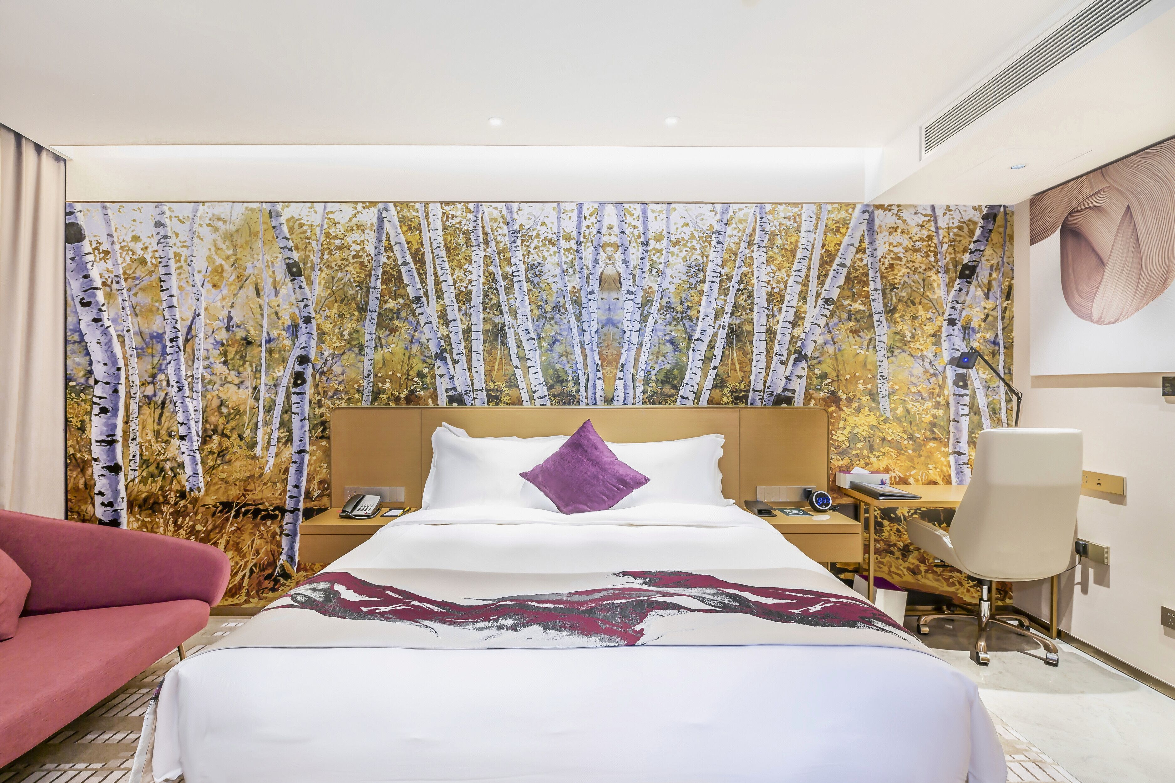 Quarto de hotel com uma cama grande, uma escrivaninha, uma cadeira e uma mesa de cabeceira.