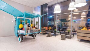 Interior moderno com carrinho de comida verde-água, área de estar e janelas amplas.
