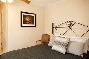 Quarto com cama, quadro na parede, cadeira e estrutura da cama com design geométrico.