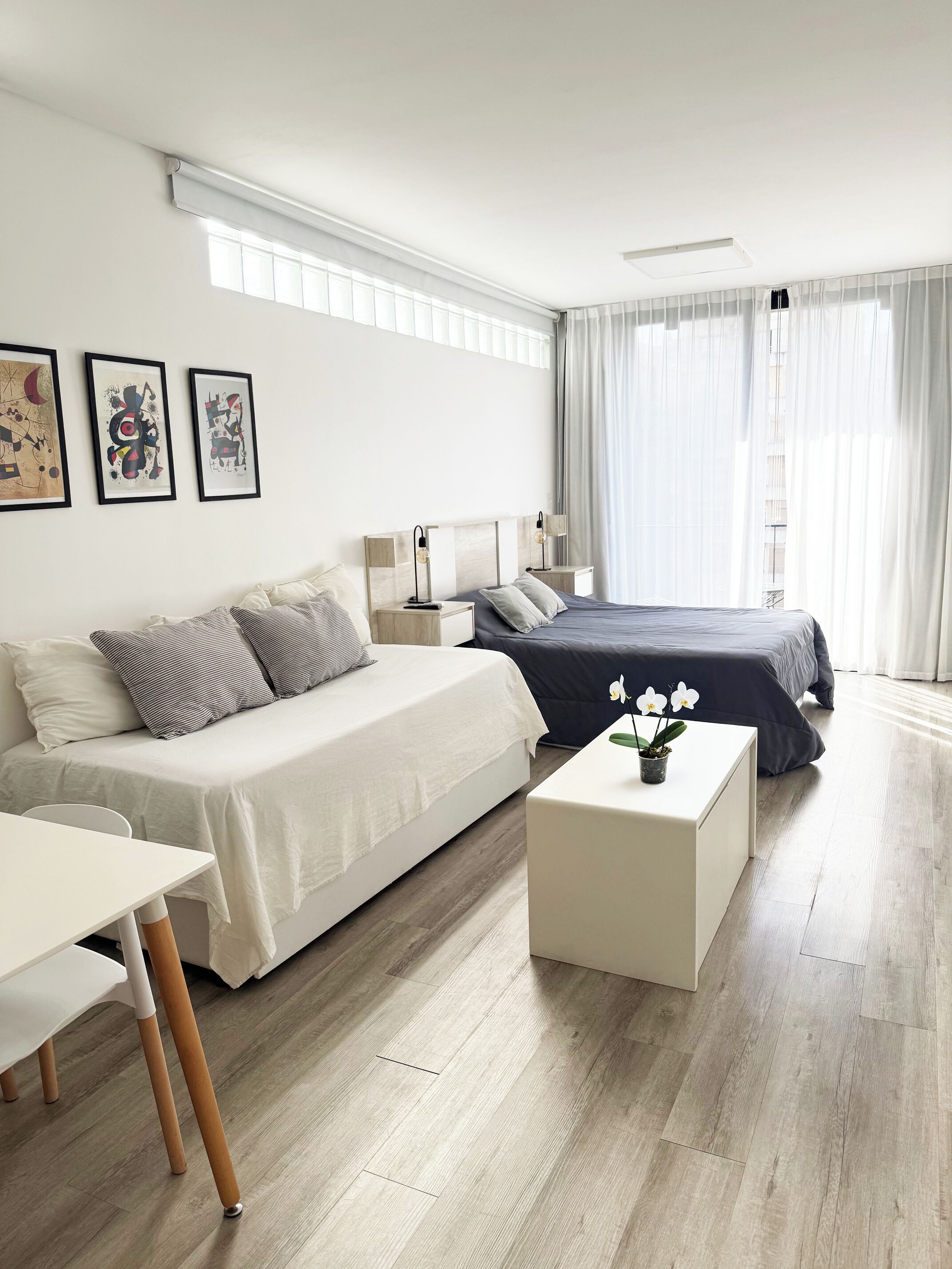 Um quarto moderno com uma cama, um sofá, uma mesa de cabeceira e uma pequena escrivaninha.