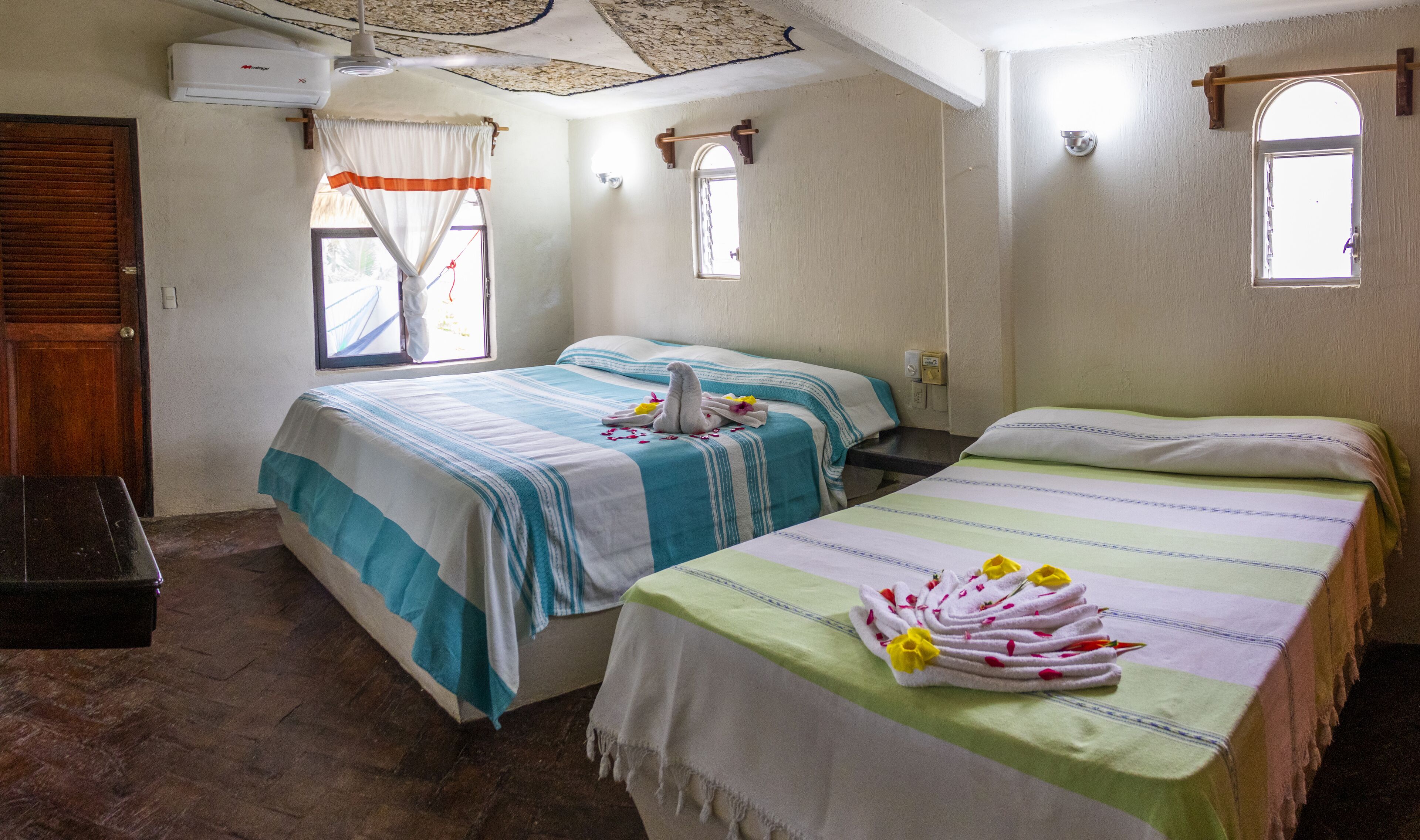 Quarto com duas camas, porta de madeira e janela com cortinas.