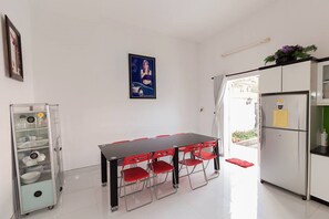 Uma cozinha limpa e moderna com uma mesa de jantar e cadeiras, uma geladeira e um escorredor de louça.
