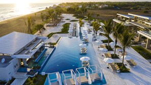Um resort com piscina central, espreguiçadeiras e vista para a praia.