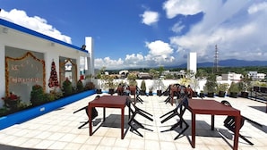 Terraço no telhado com mesas e cadeiras, vista da cidade e decoração festiva.