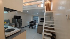 Cozinha compacta com micro-ondas, geladeira e área de refeições com cadeiras.