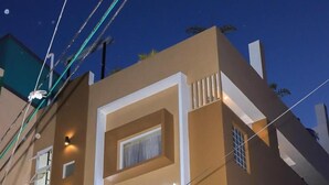 Uma pousada chamada 'Rosetta Guest House', com design moderno, apresentando várias varandas e uma placa iluminada em destaque.
