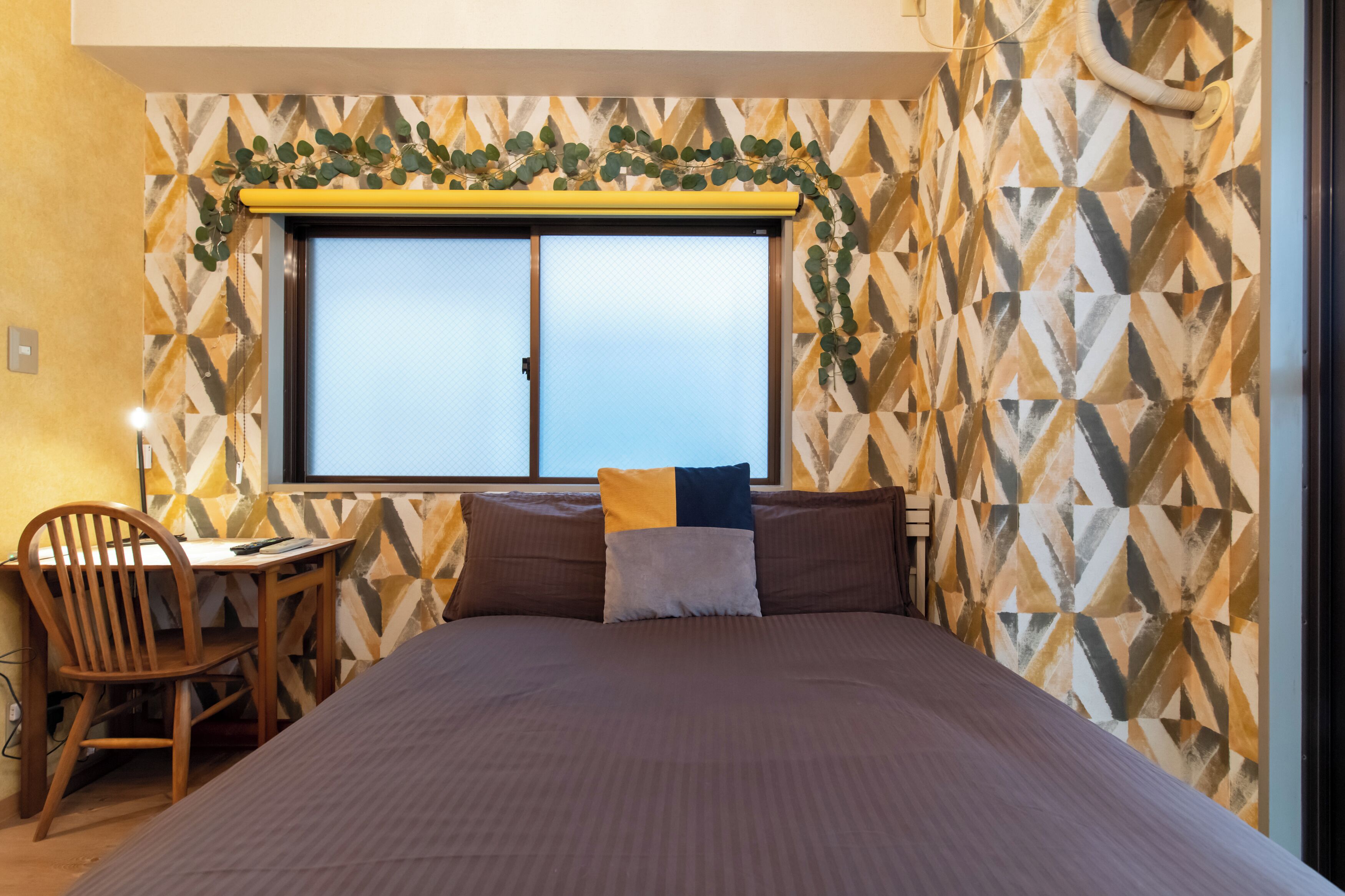 Quarto com cama, escrivaninha e cadeira.