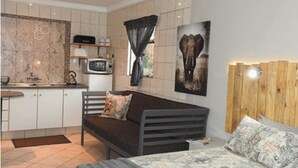 Um espaço compacto com cozinha compacta, sofá, cama e cabeceira de madeira.