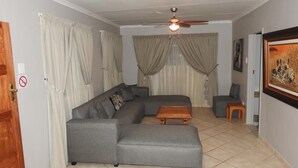 Uma sala de estar com um sofá seccional cinza, uma mesa de centro de madeira e um ventilador de teto.