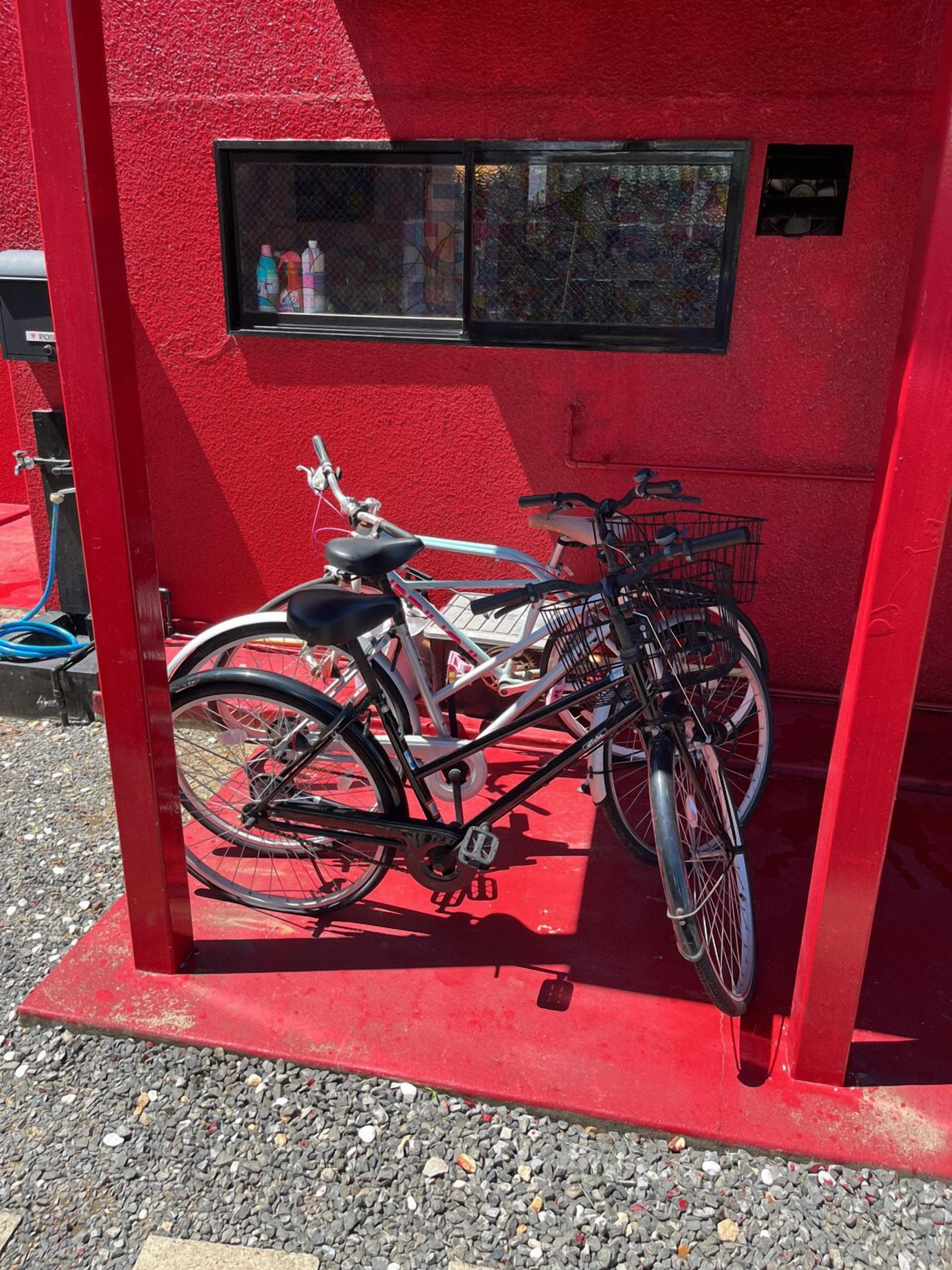 Um armário vermelho para guardar bicicletas, com duas bicicletas lá dentro.