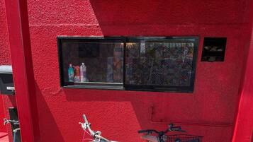 Um armário vermelho para guardar bicicletas, com duas bicicletas lá dentro.