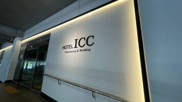 Entrada de um hotel com uma placa que diz 'HOTEL ICC Convention & Wedding'.