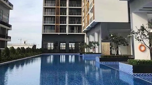 Um edifício moderno alto com uma piscina em frente.